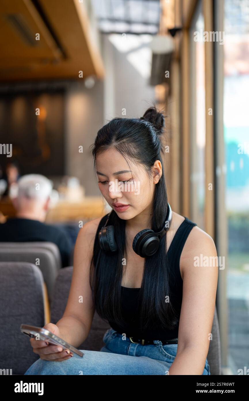A beautiful, thoughtful Asian woman carefully reads text messages on ...