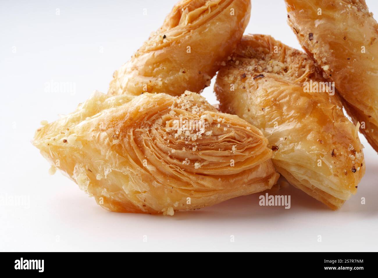 Crispy pastry dessert filled with nuts and syrup showcased on a white ...