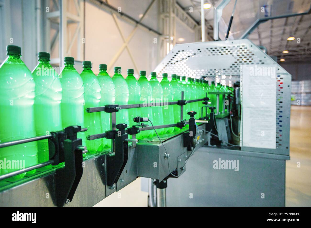Bottling process in a factory with green plastic bottles moving along a ...