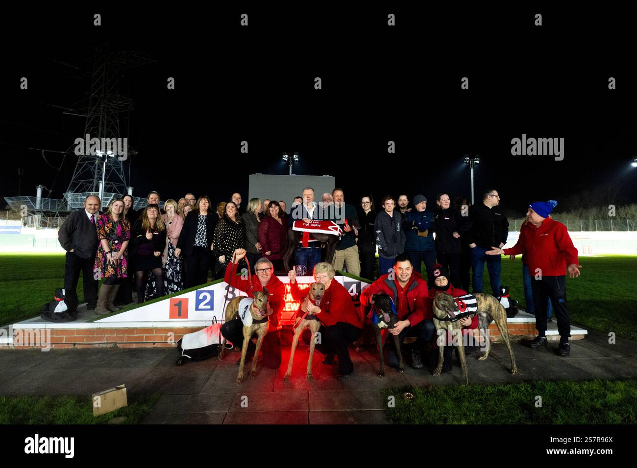 Staff members pose with greyhounds at the podium during the final night ...