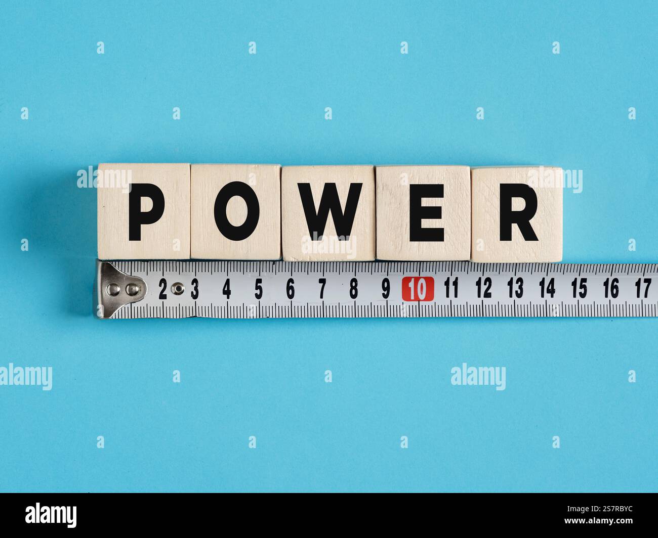 Wooden cubes forming the word power are measured with a tape measure, symbolizing power ...