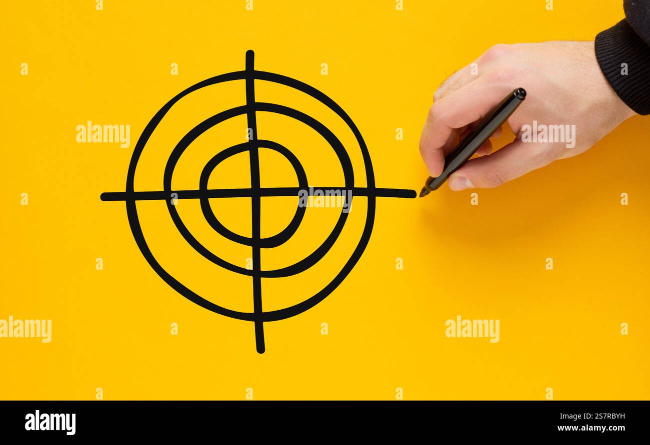 Hand drawing a target on a vibrant yellow background, representing the ...