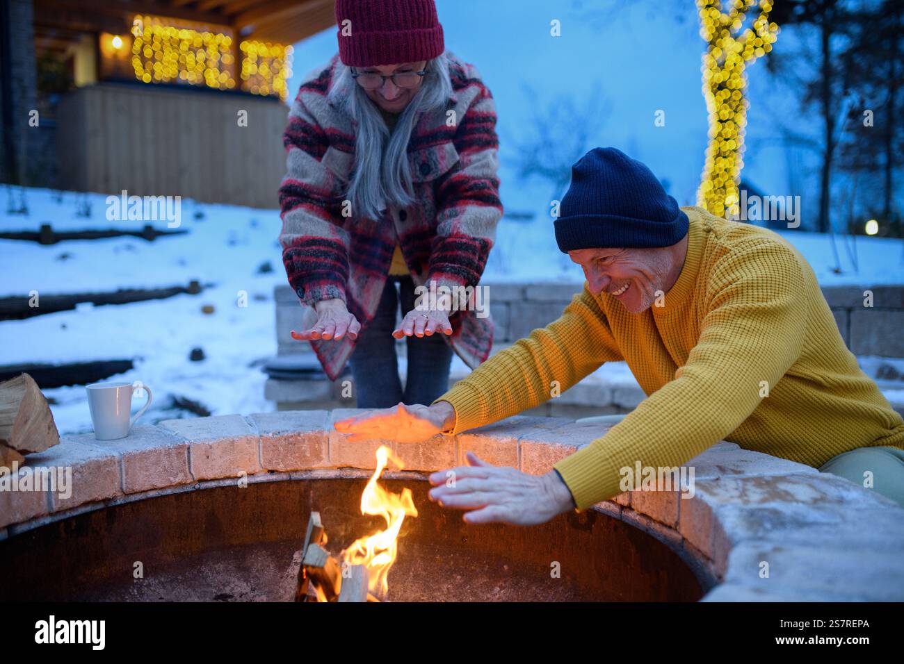 Older couple has lit a fire in garden fire pit. Seniors watching flames ...