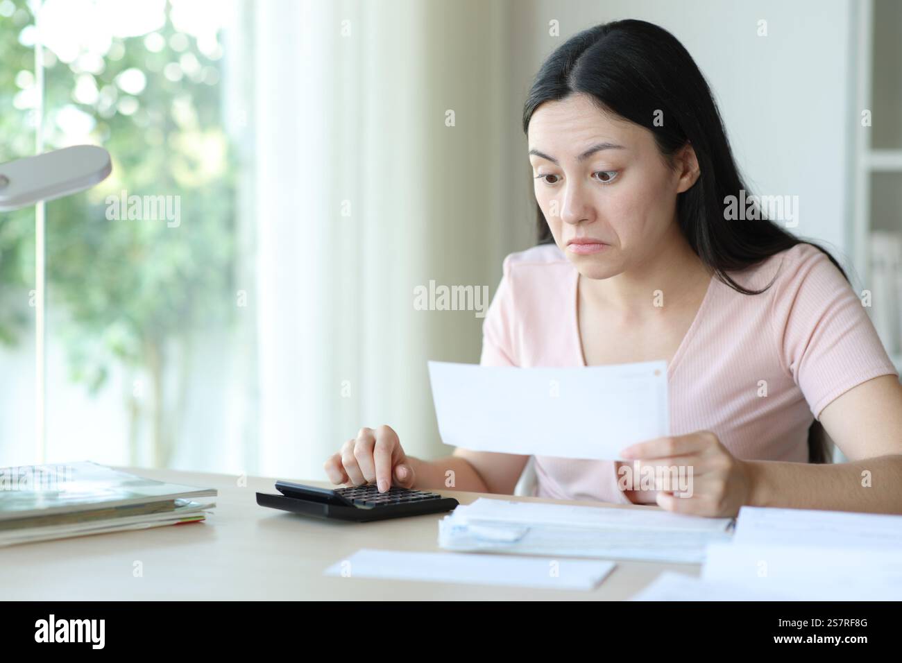 Perplexed asian woman checking incomprehensible receipt in a desk at home Stock Photo - Alamy