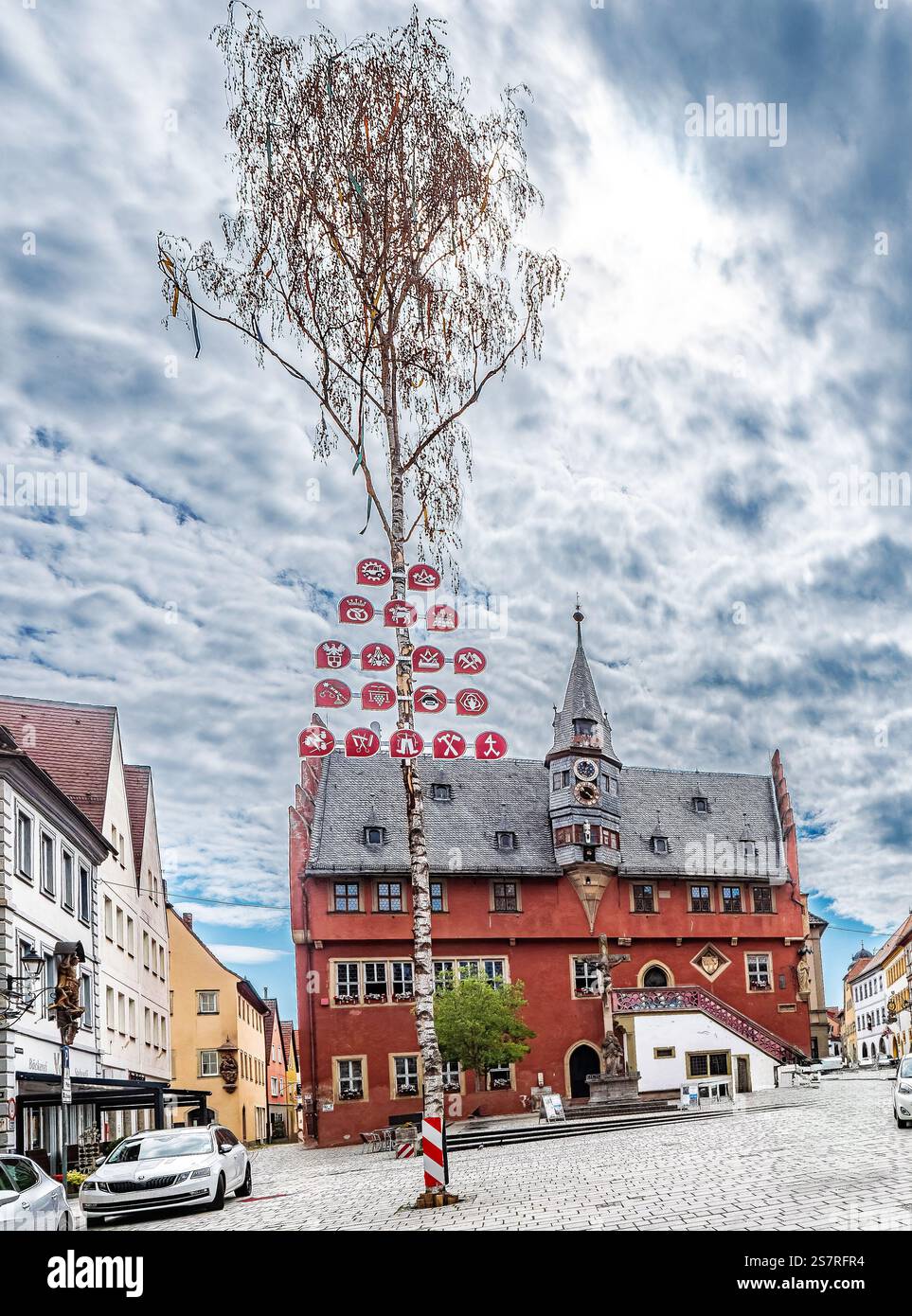 A traditional maypole adorned with symbols stands in front of a ...