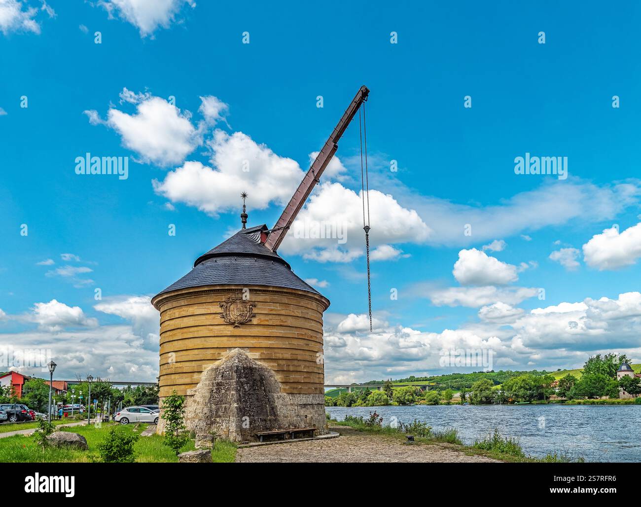 A historical wooden crane by the riverside under a vibrant blue sky ...