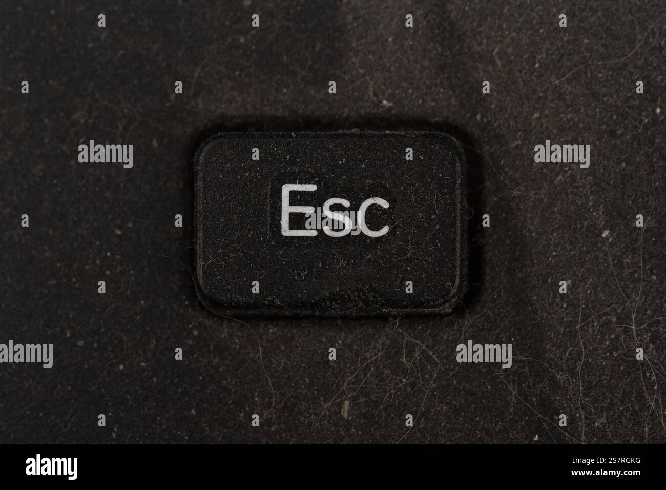 front view closeup of escape key on an old black keyboard covered in ...