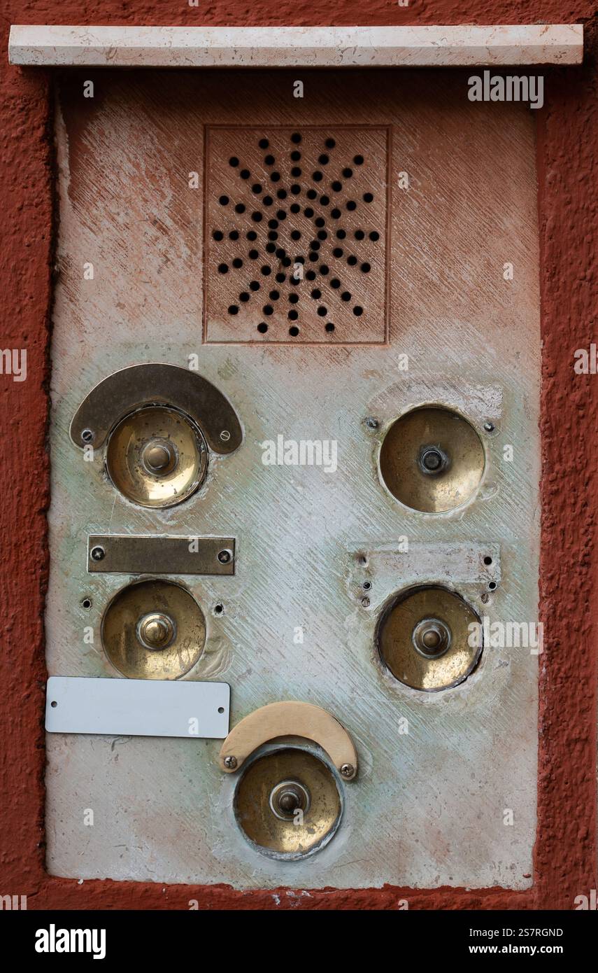 A vintage intercom panel featuring multiple bronze buttons set on a ...