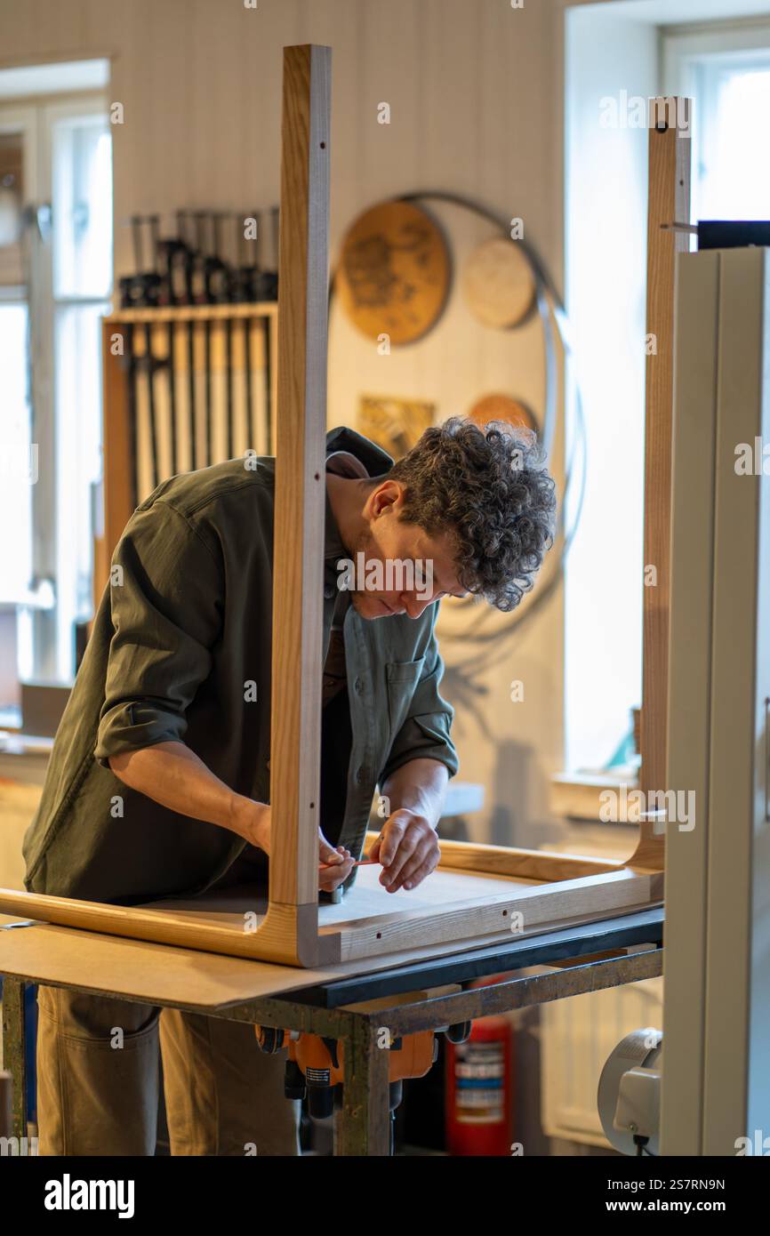 Craftsman attaches legs to table base, completing assembly in workshop ...