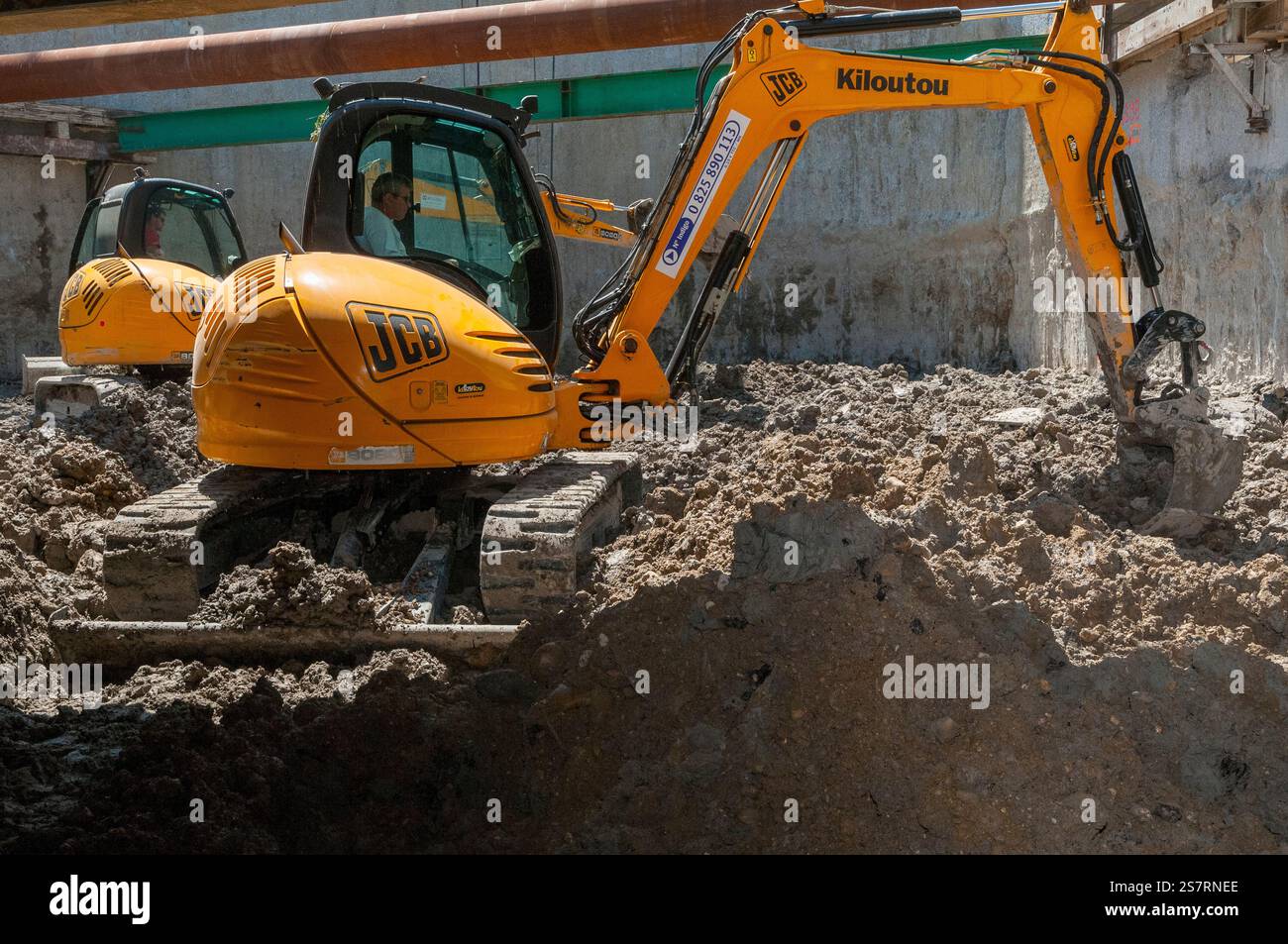 Two mini excavators busy digging earth on a construction site. France ...