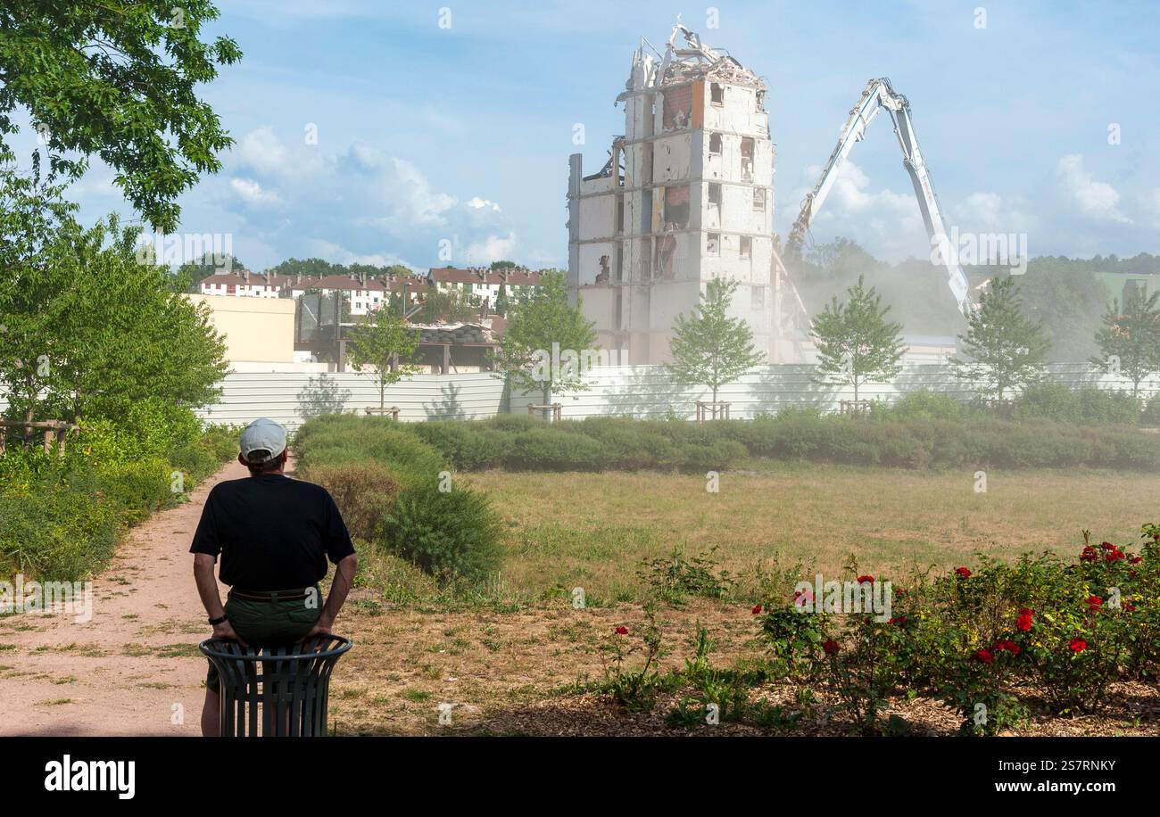 A man seen from behind watches the demolition of his old building using ...