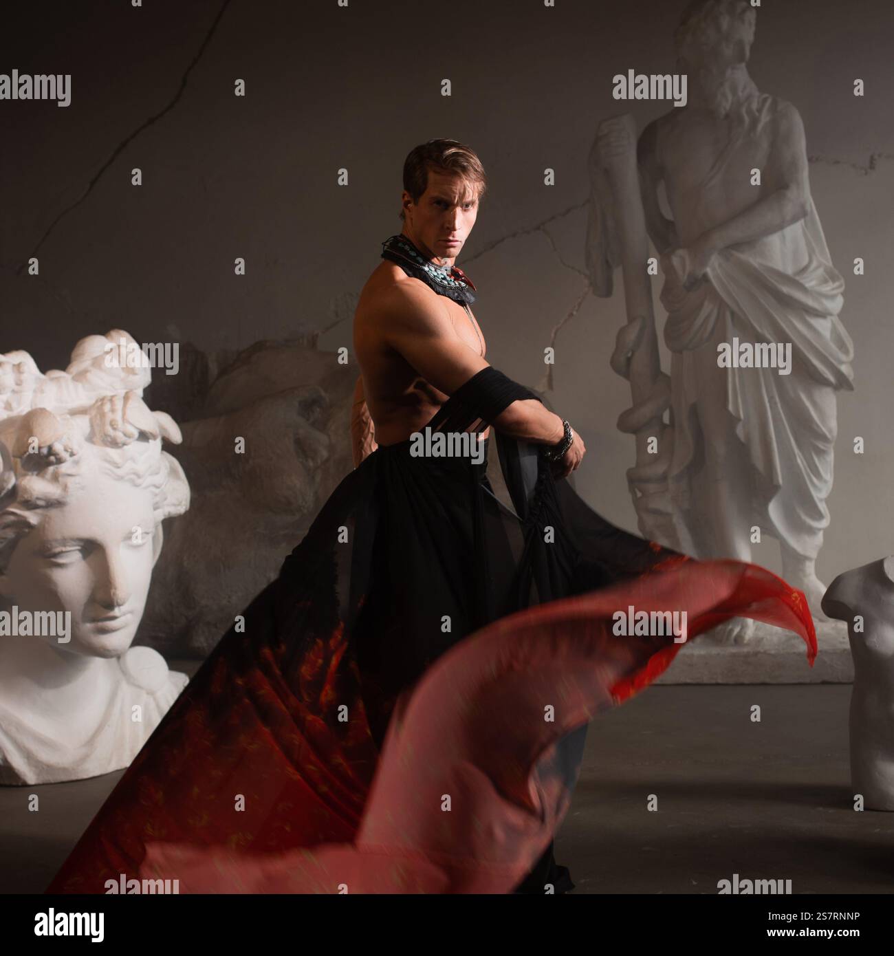 Muscular charismatic bodybuilder model in a silk cape makes an ...