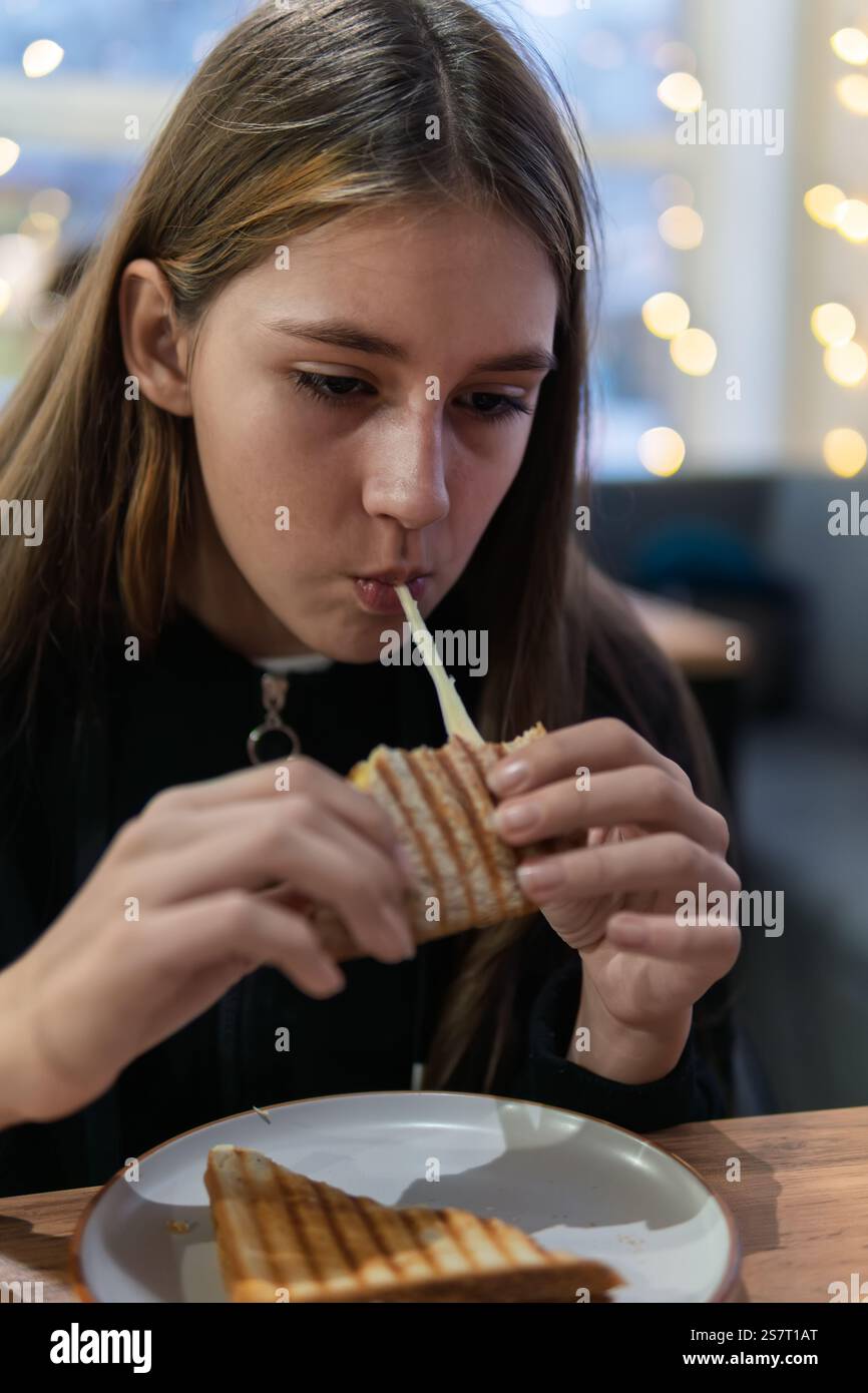 Teenage girl eats sandwich. girl holds a sandwich in his hands and eats ...