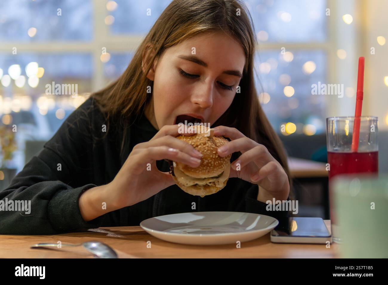 Teenage girl eats burger. girl holds a burger in his hands and eats at ...