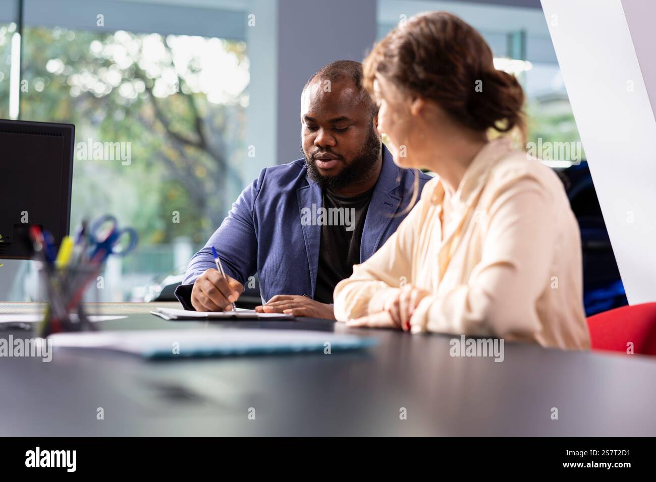 Clients signing contract after being shown dealership vehicles by car ...