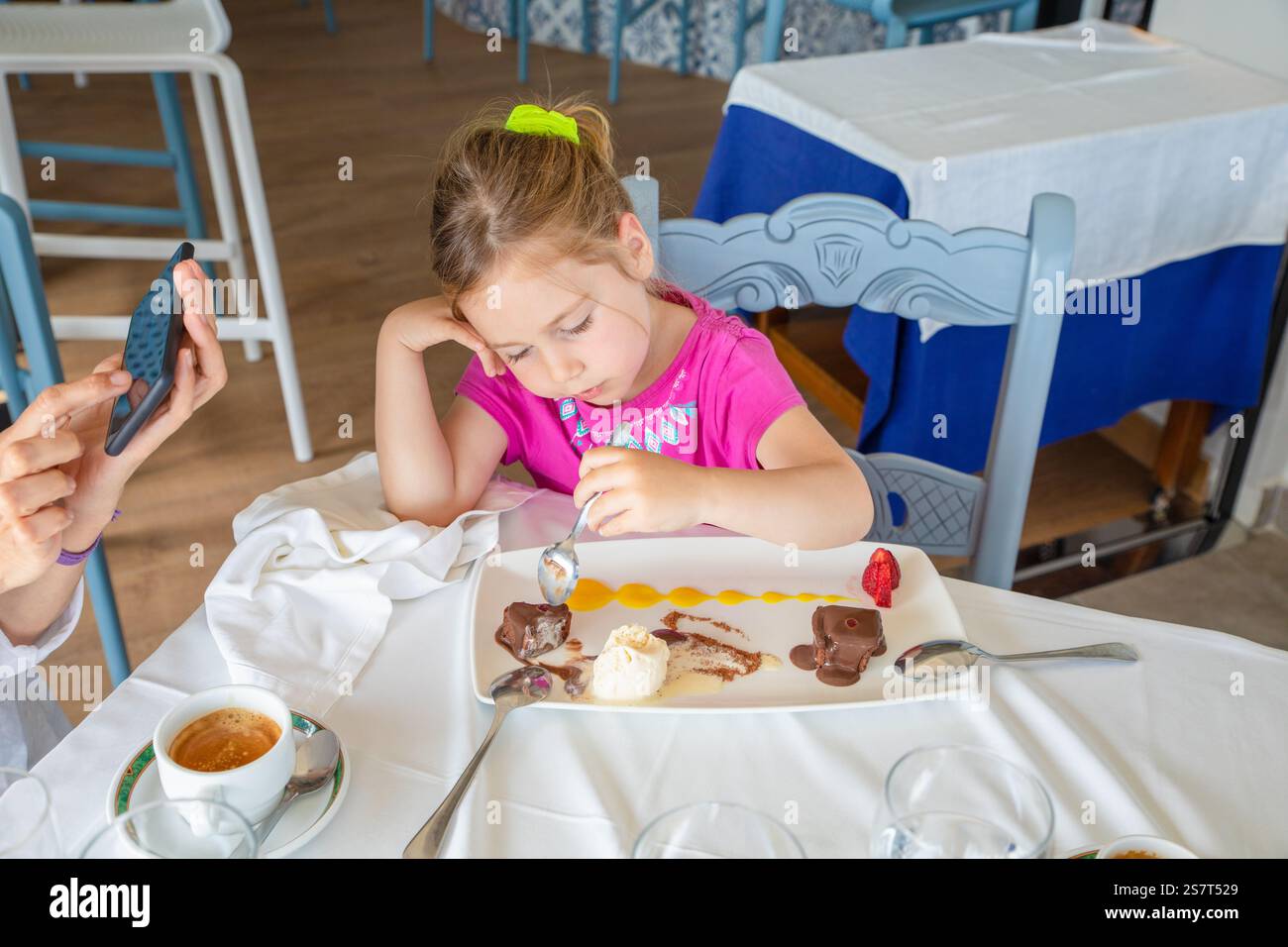 four years old blonde girl eating sweet dessert: black chocolate ...