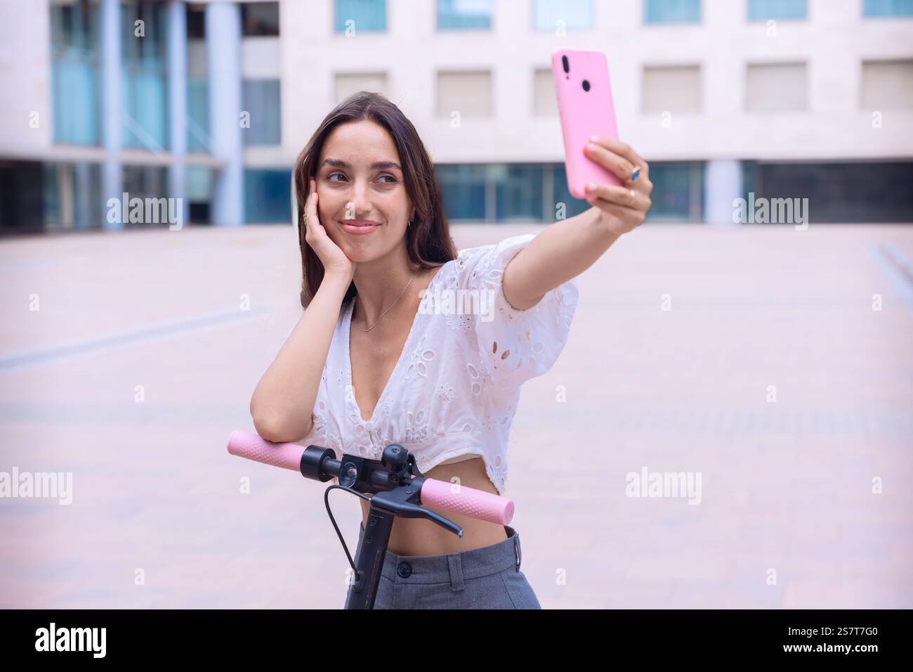 Young woman taking a selfie with smartphone while leaning on scooter ...