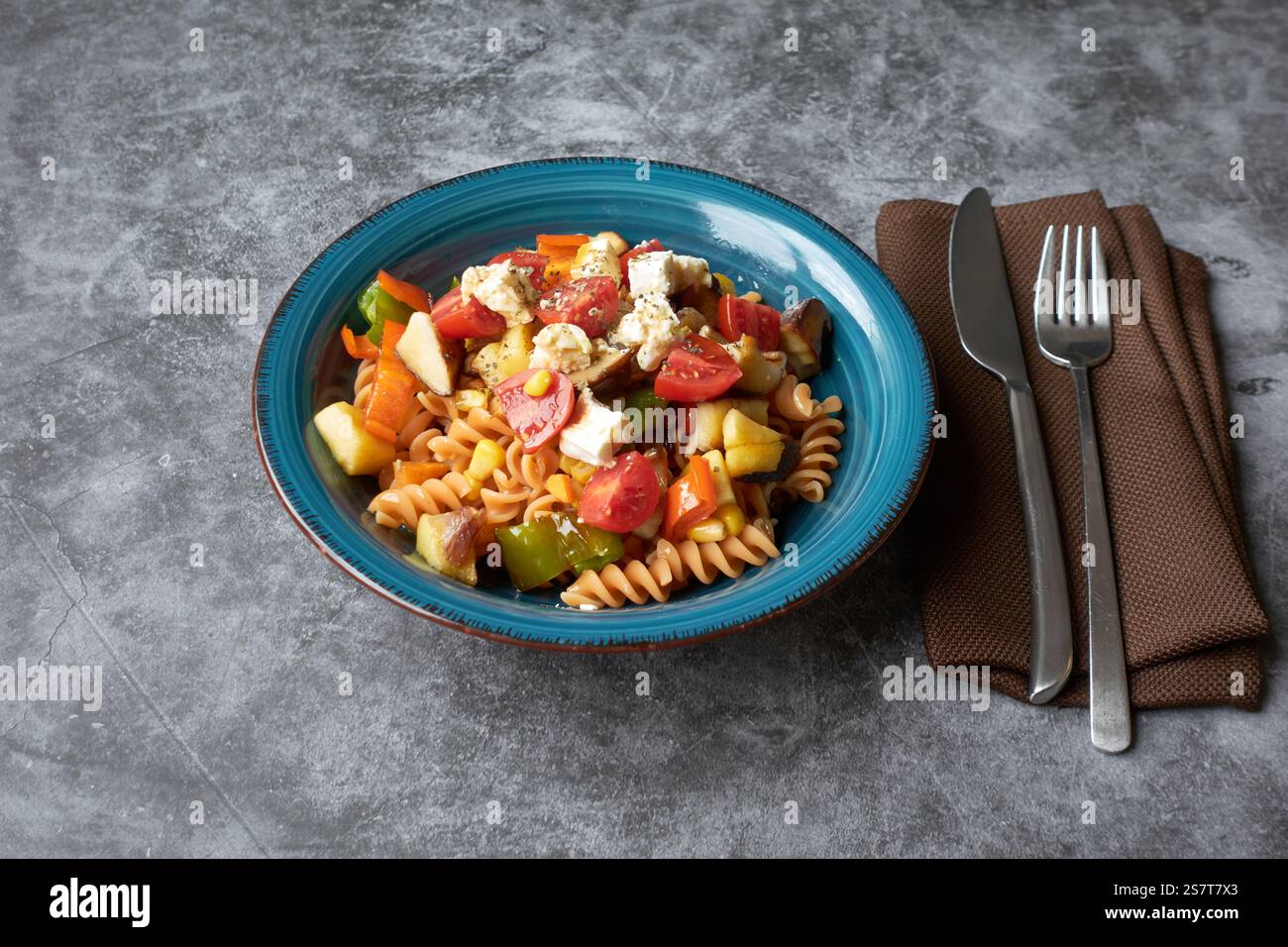 Fresh pasta salad with tomatoes, cheese cubes and vegetables in a ...