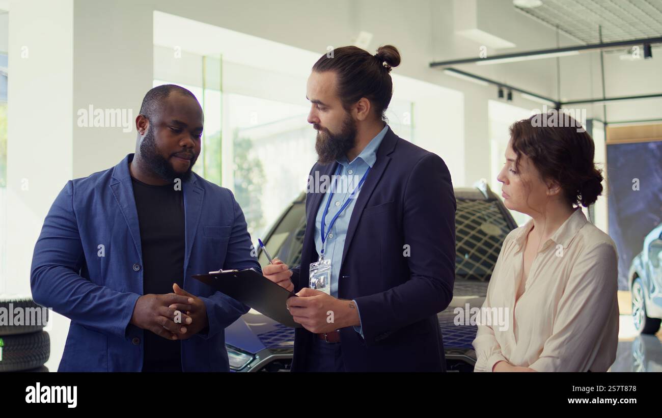 Friendly car salesman showcasing dealership vehicles to clients ...