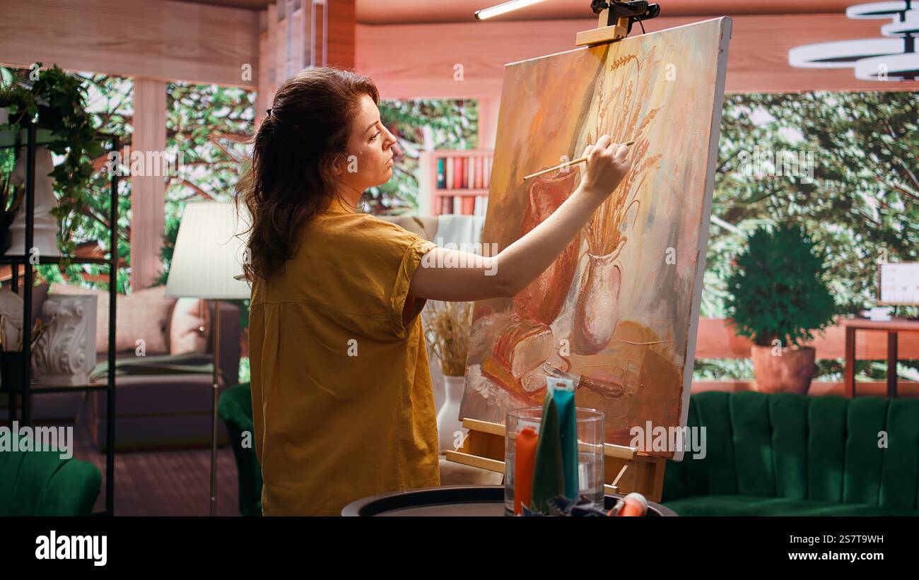 Skilled artist stands before an easel painting a watercolor rustic ...