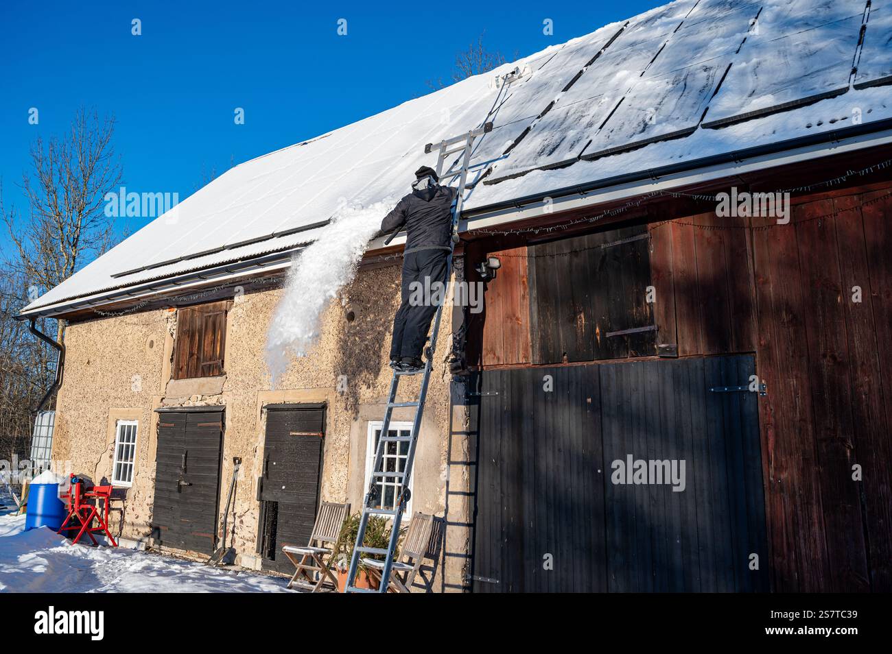 Man removing snow from solar panels on roof Stock Photo - Alamy