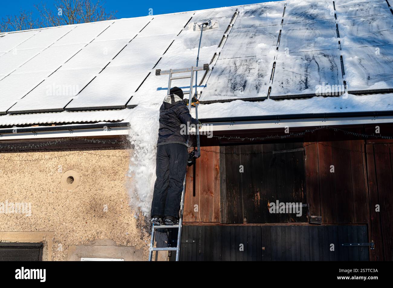 Man removing snow from solar panels on roof Stock Photo - Alamy