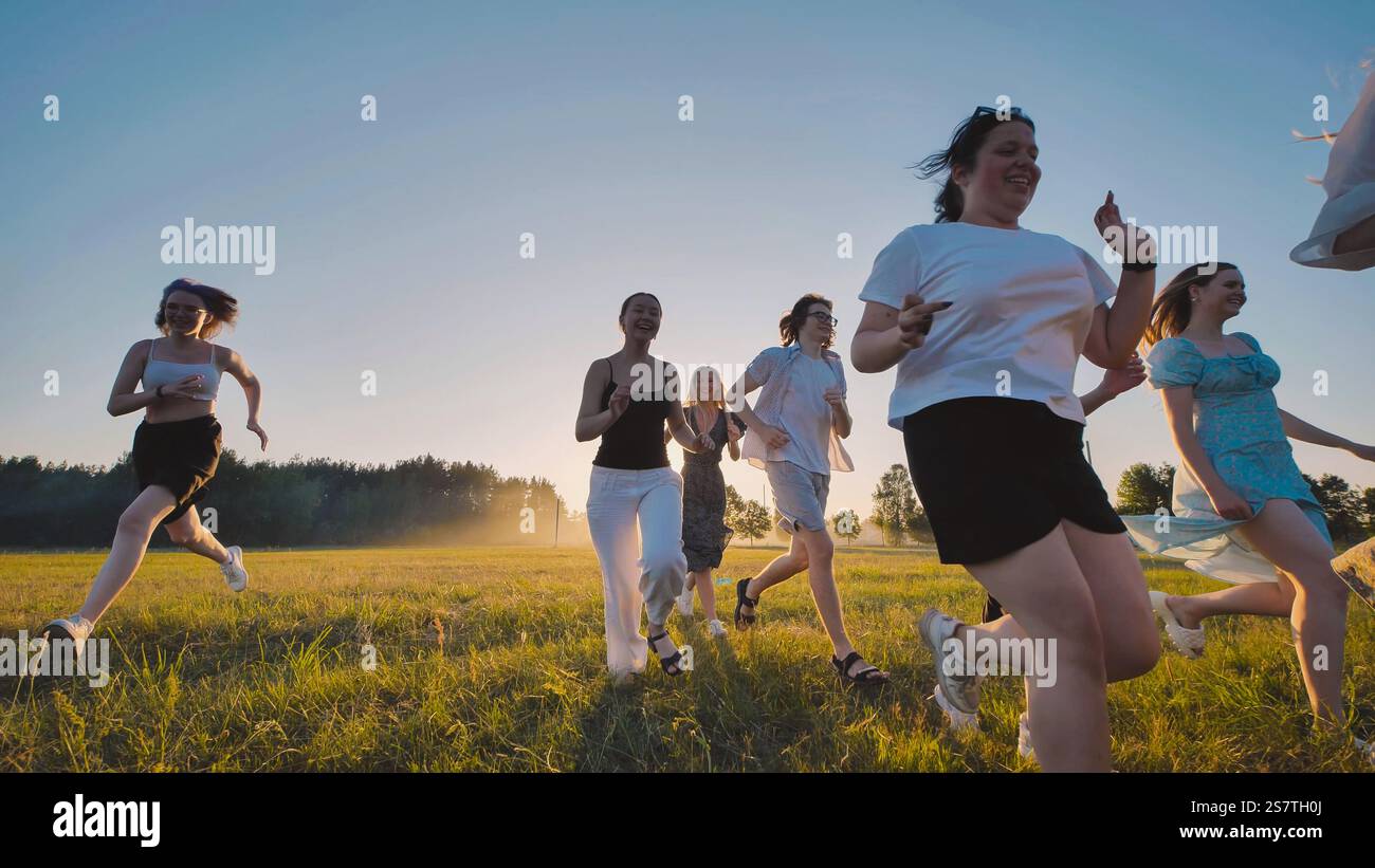 Happy high school students running together in a field at sunset ...