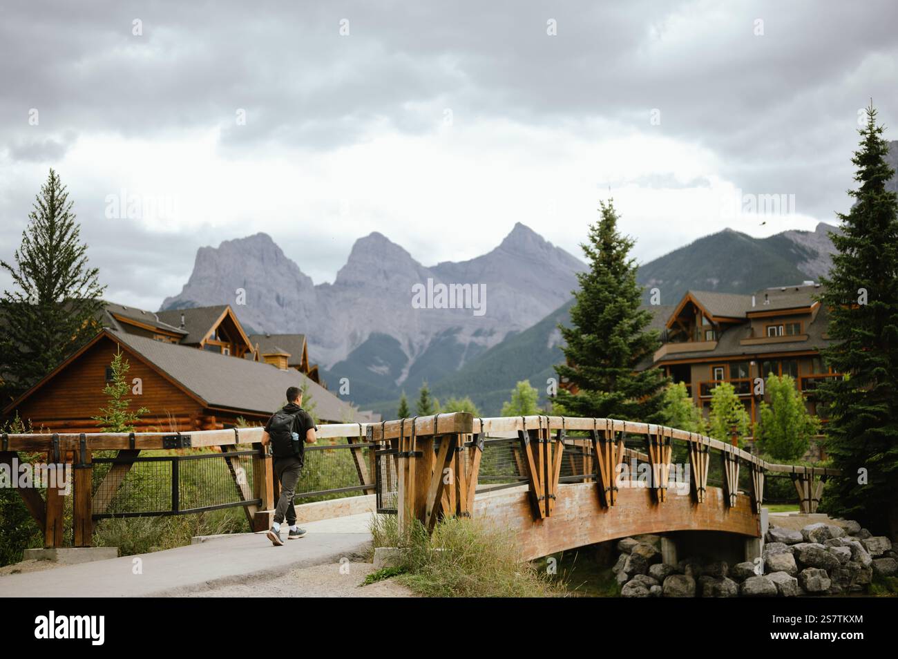 Man walking on wooden bridge with mountains in Canmore, Canada Stock ...