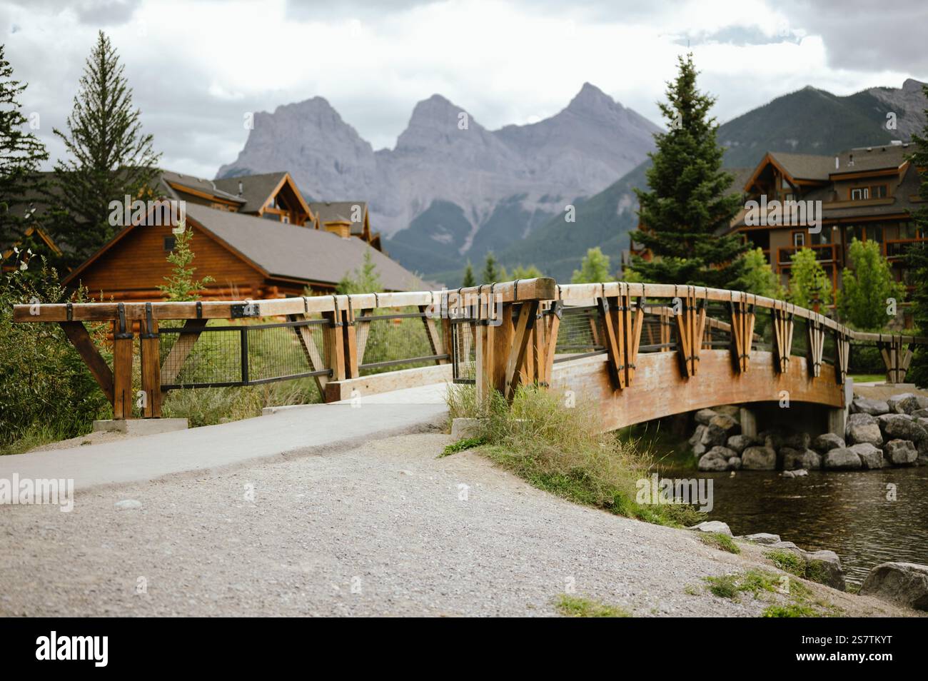 Wooden bridge over water with mountain and downtown Canmore backdrop ...