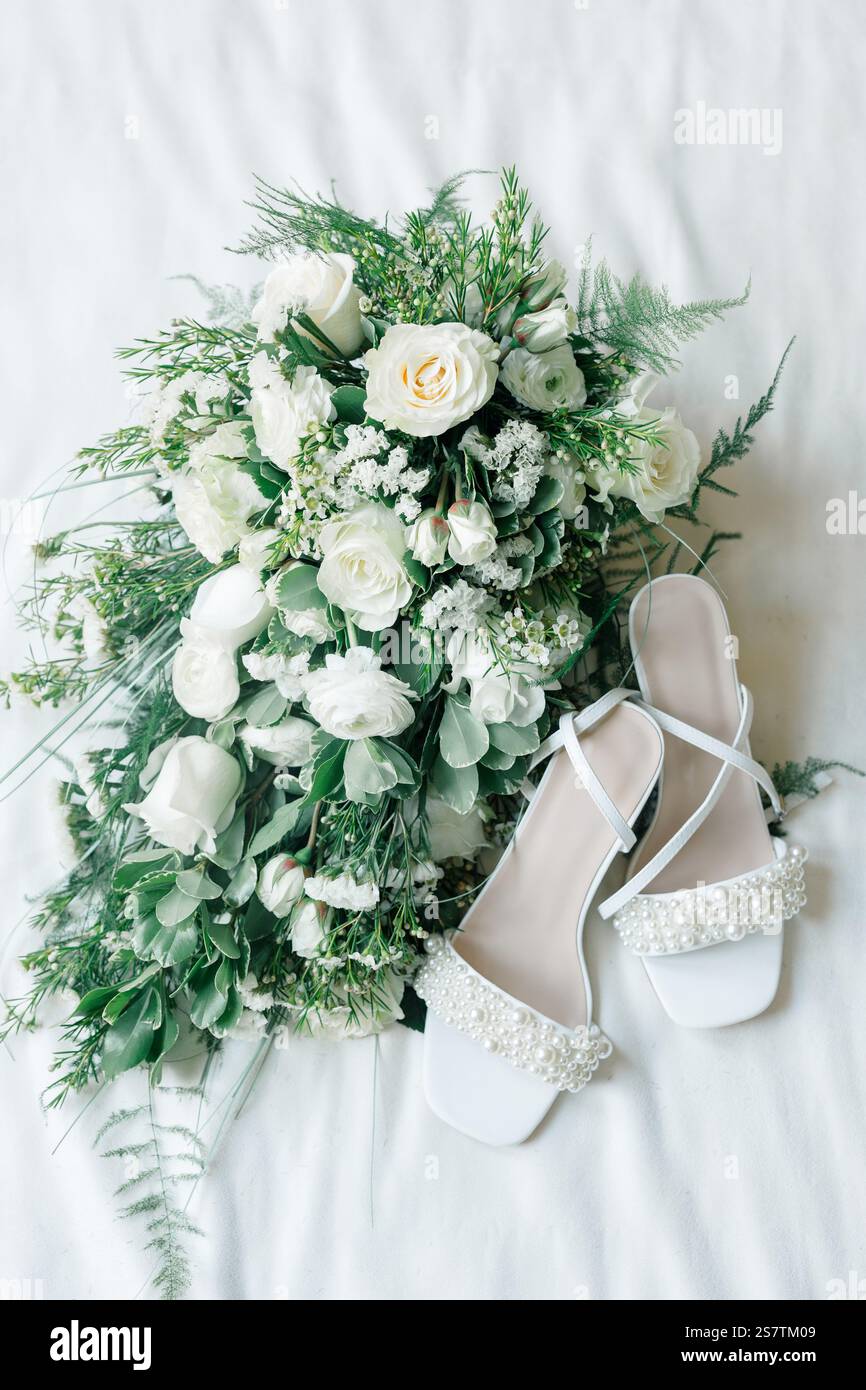 Bridal bouquet white roses, ranunculus, and greenery and pearl heels ...