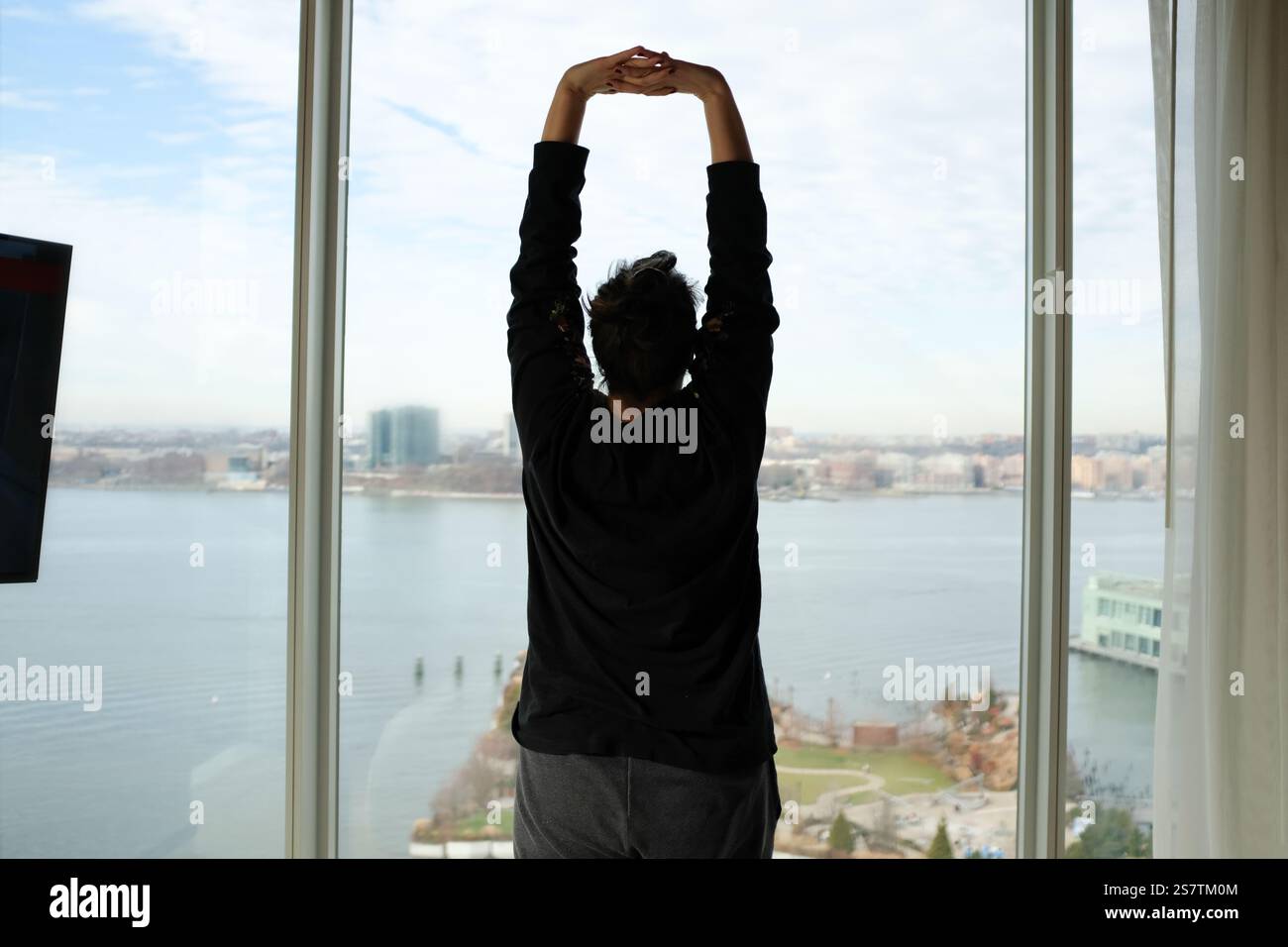 Woman Stretching In front of Large Scenic Window Looking at River Stock ...