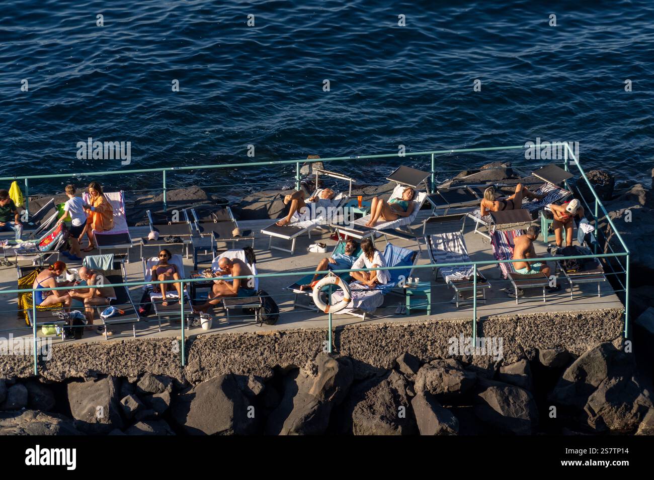 Tourists sunbathing on a recreation pier in the Bay of Naples at ...