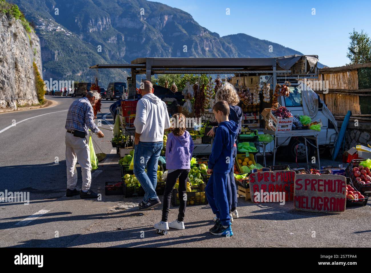 A roadside vendor selling fresh produce to a family by the Amalfi Coast ...