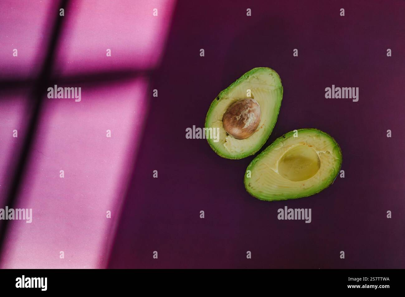 Avocado cut in half in dramatic light with purple background Stock ...