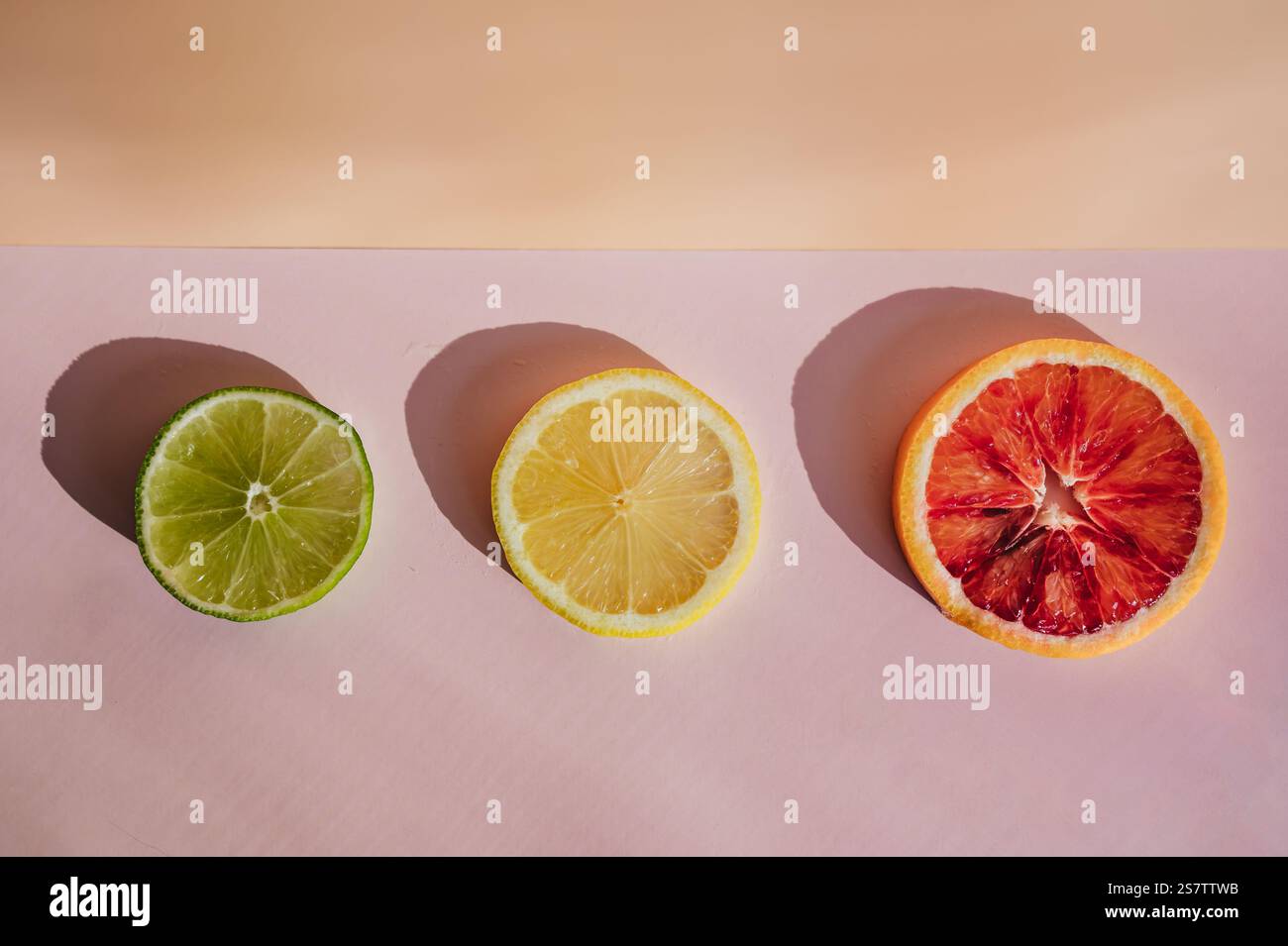 Flat lay of sliced lemon, blood orange, and limed with pink background ...