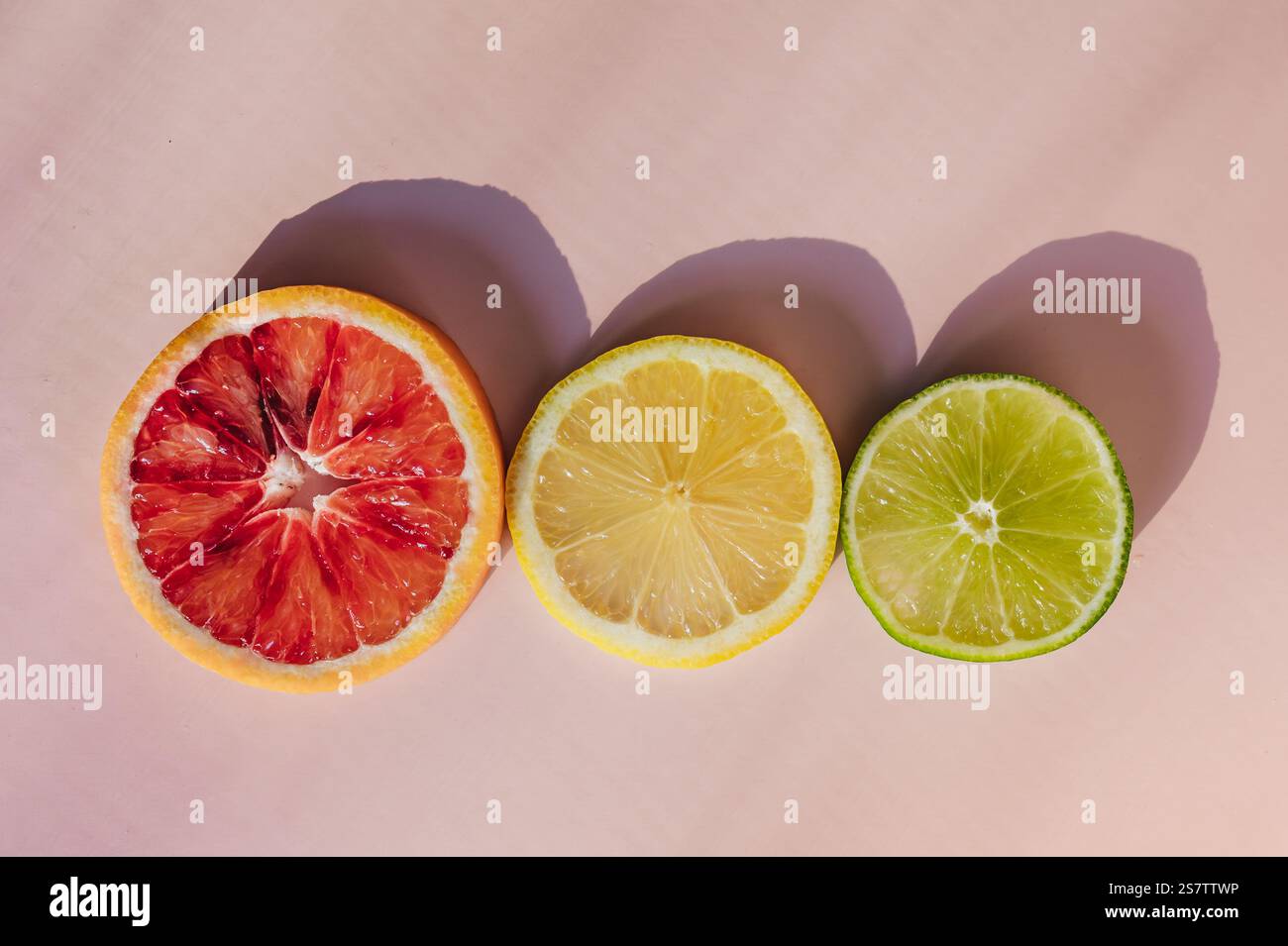 Flat lay of sliced lemon, blood orange, and limed with pink background ...