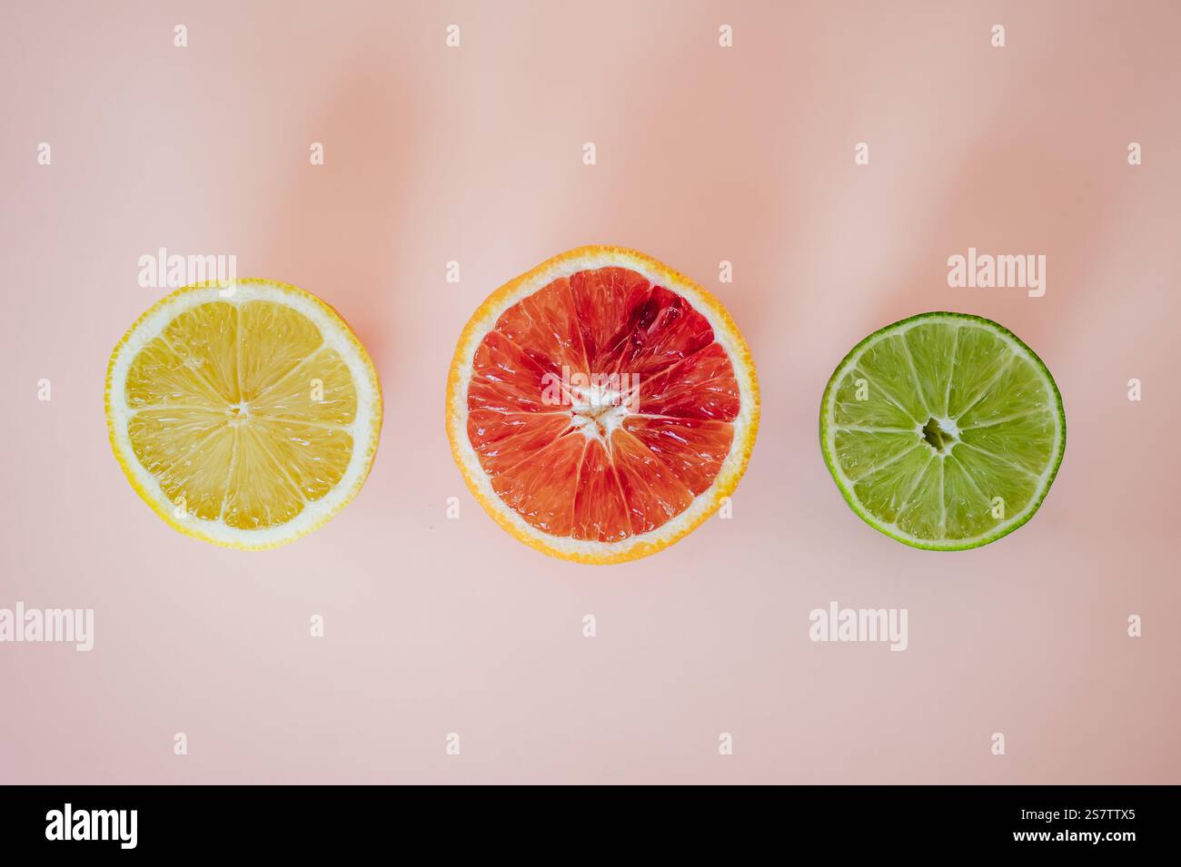 Flat lay of sliced lemon, blood orange, and limed with pink background ...