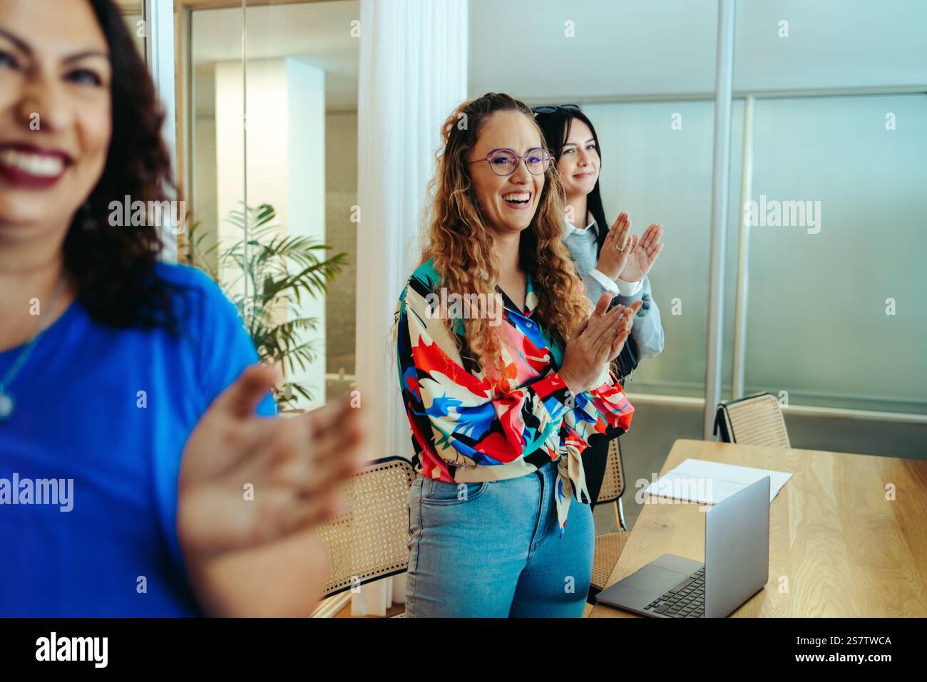 A group of female coworkers clapping in appreciation, exuding a sense ...