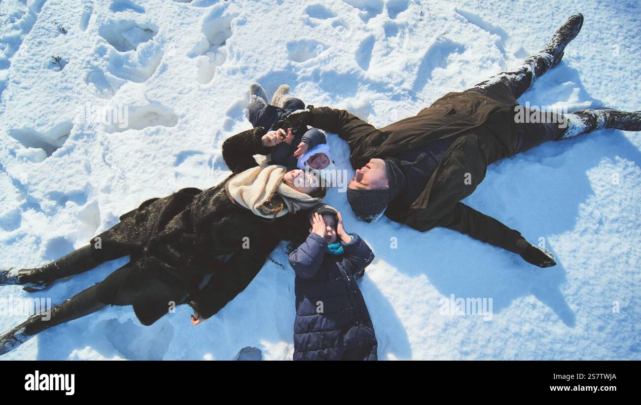 Winter family moment, parents and kids creating snow angels, laughing ...