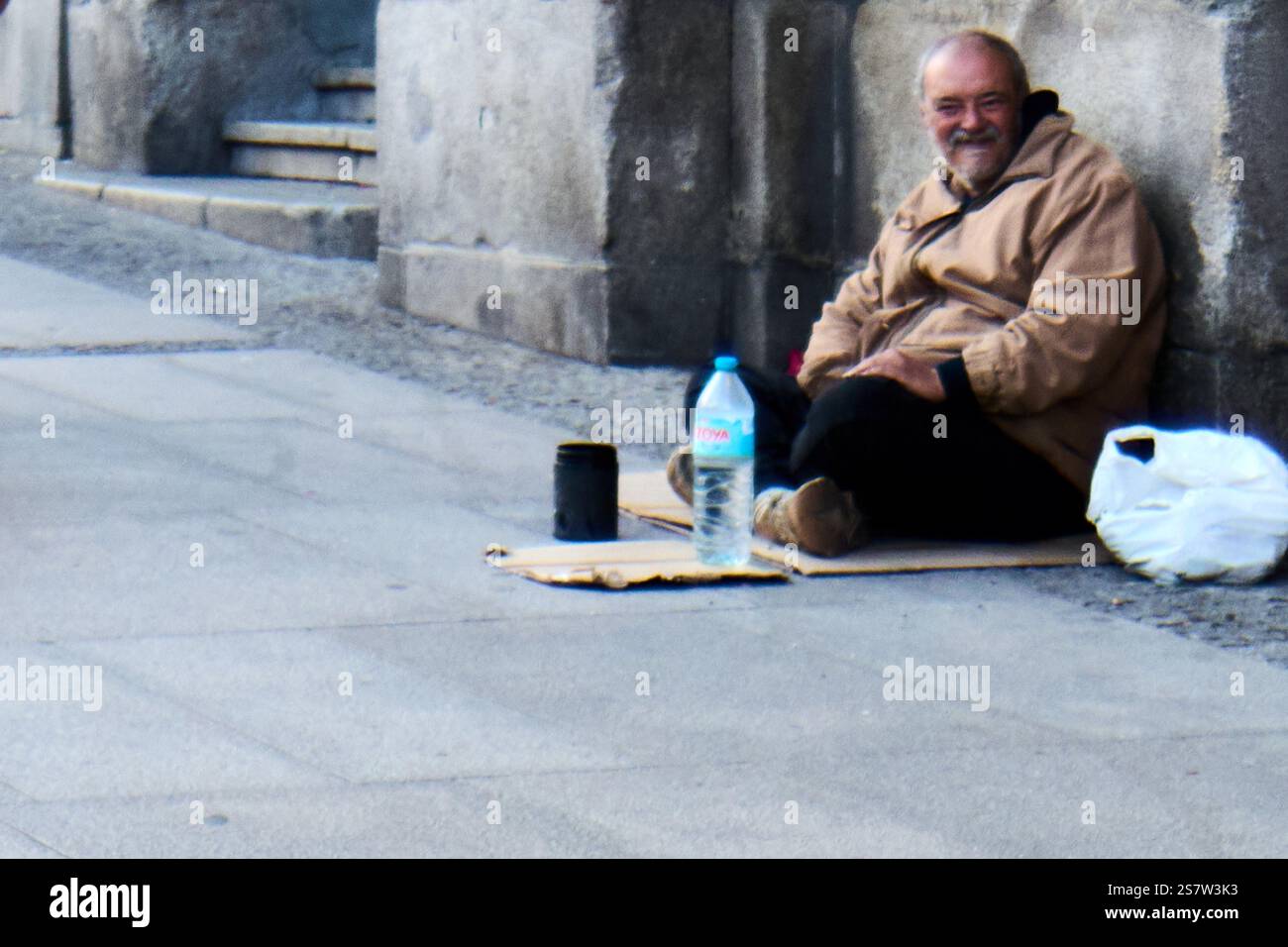 Madrid, Spain - January 20, 2025: Homeless person in brown coat sitting ...