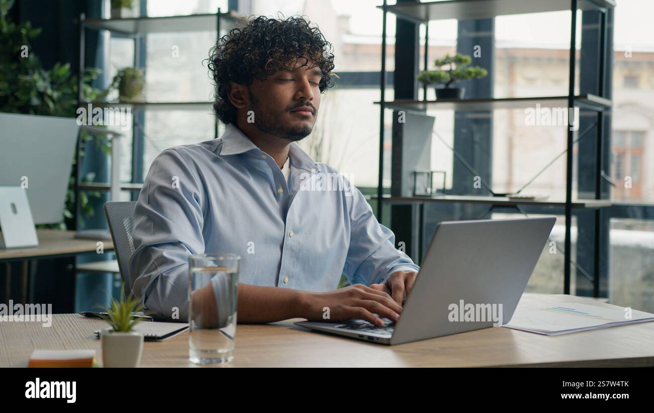 Tired Arabian Indian man businessman working on laptop relaxed male ...