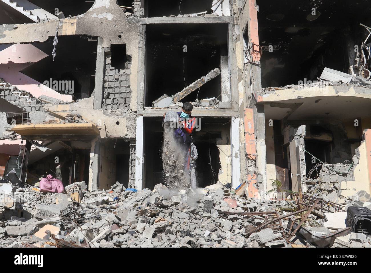 A man clears rubble from a building destroyed during the Israeli ...