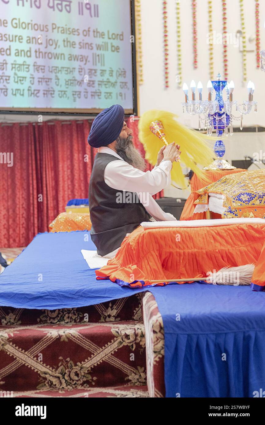 A SIkh priest waves a yellow flag - chaur sahib - during services at a ...