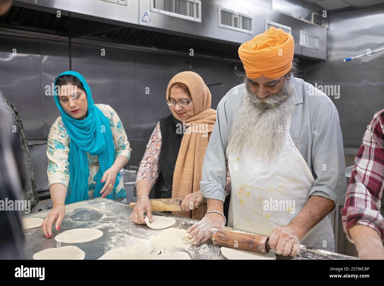 Sikh men & women press dough into discs while preparing roti breads for ...
