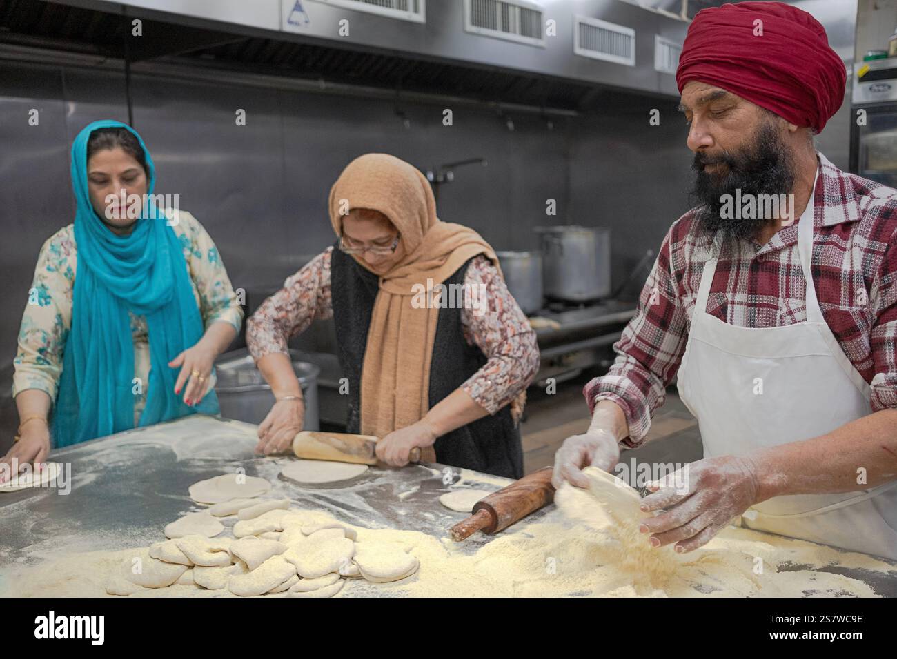 Sikh men & women press dough into discs while preparing roti breads for ...