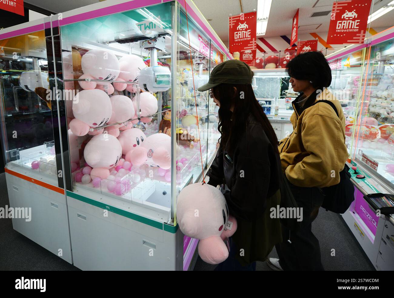 Japanese teenagers trying to pick toys in a toy crane claw machine ...
