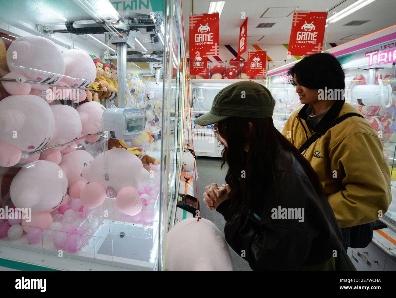 Japanese teenagers trying to pick toys in a toy crane claw machine ...