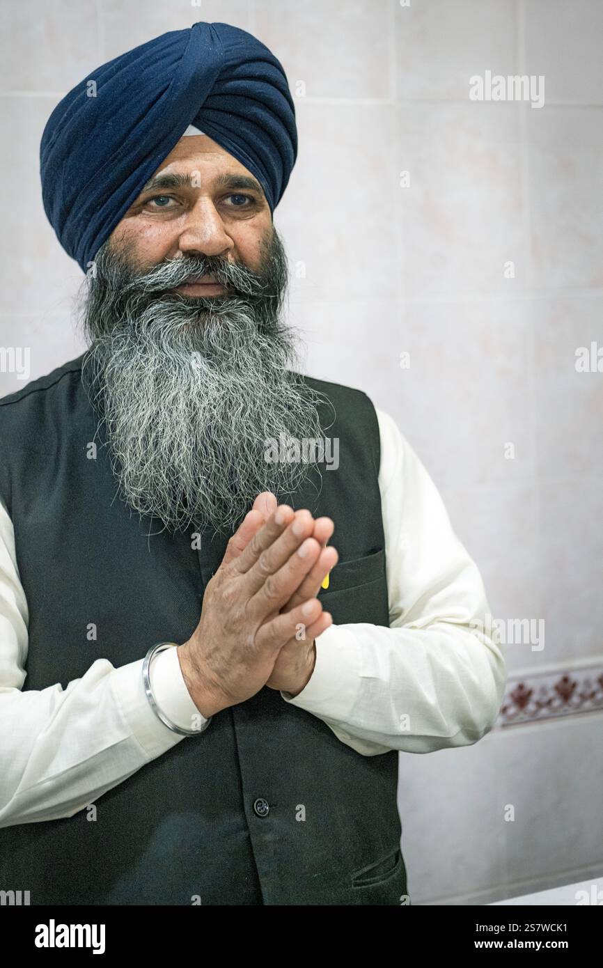 Posed portrait of a Sikh priest with his hand clasped. At a temple in ...