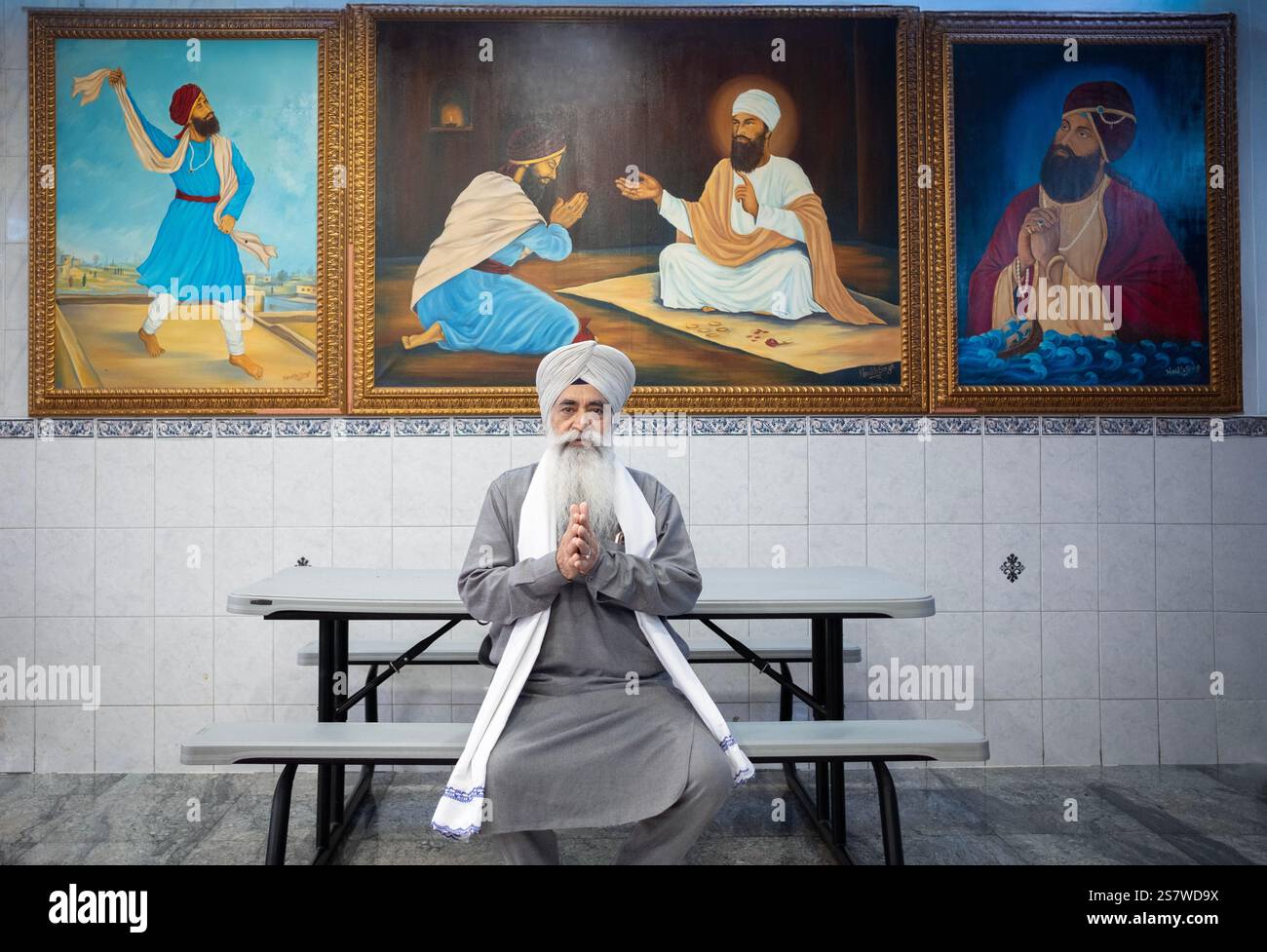 Posed pic of a distinguished Sikh priest in front of paintings of ...
