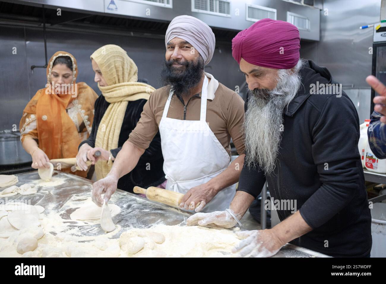 Sikh men & women prepare roti breads to be distributed in their temple ...